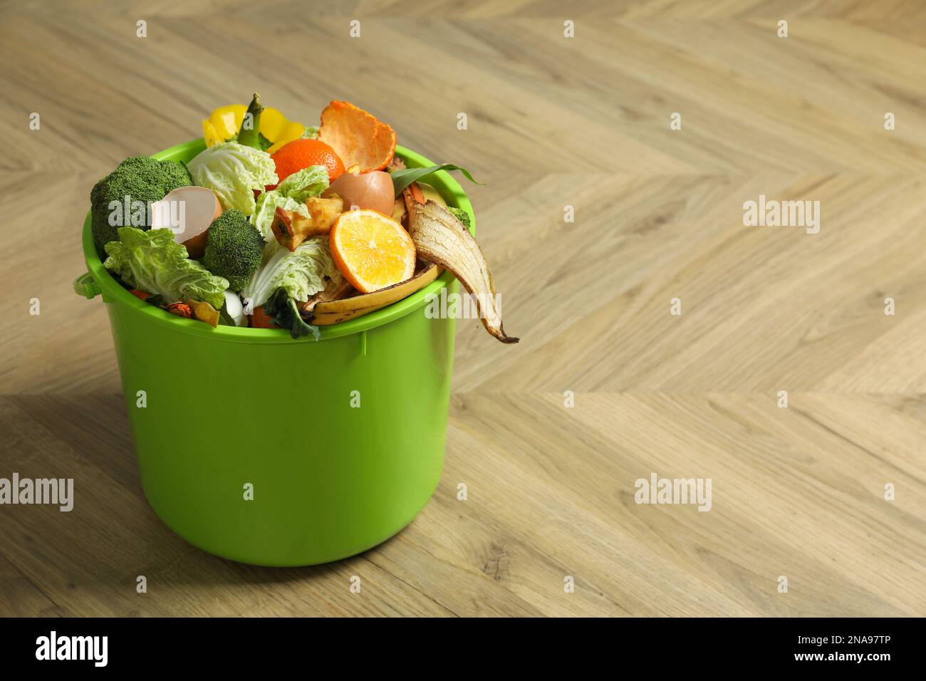 Trash bin with natural garbage on wooden background, space for text ...