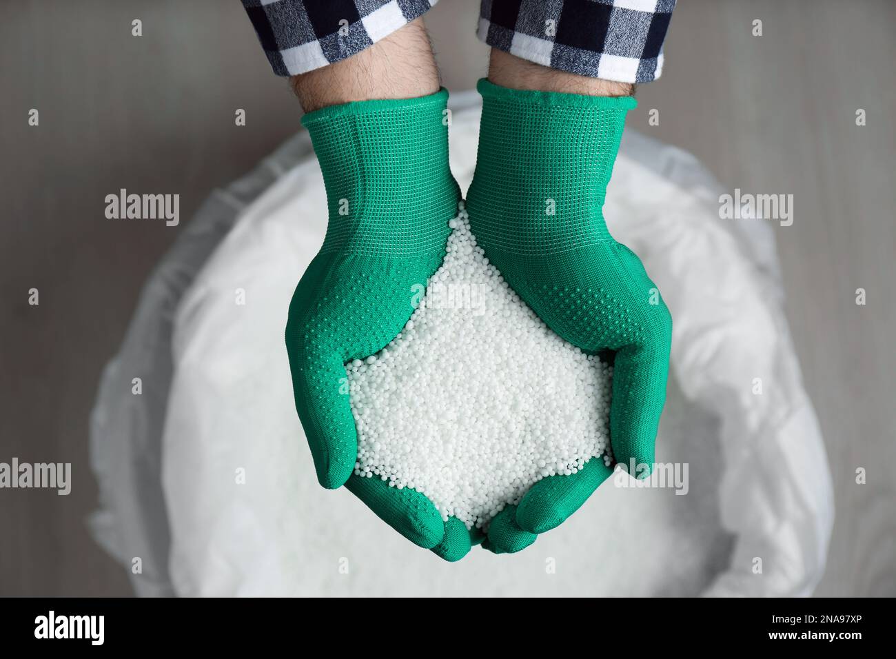 Farmer holding pile of ammonium nitrate pellets over bag, top view ...