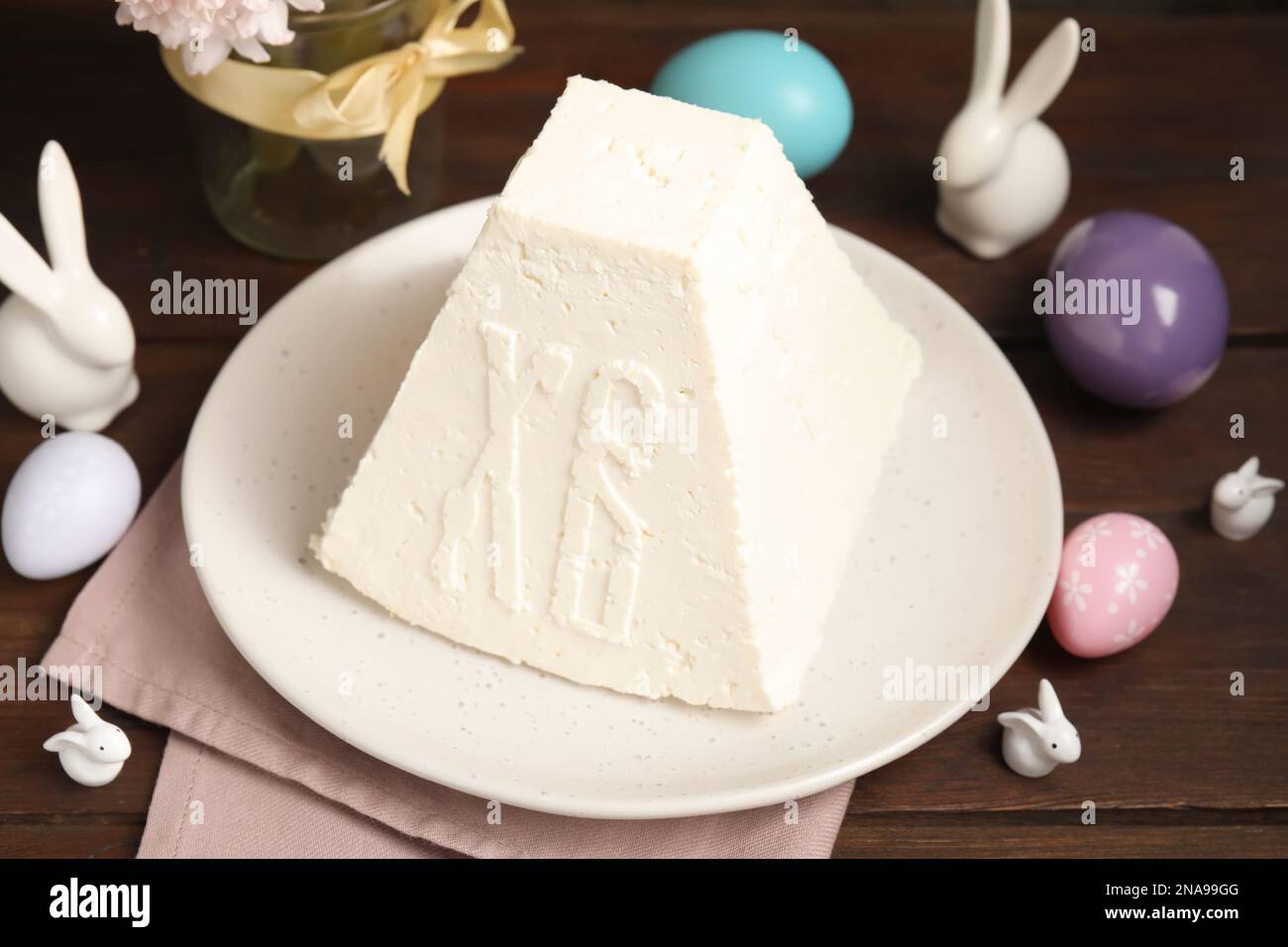 Traditional cottage cheese Easter paskha, painted eggs and decorative bunnies on wooden table ...
