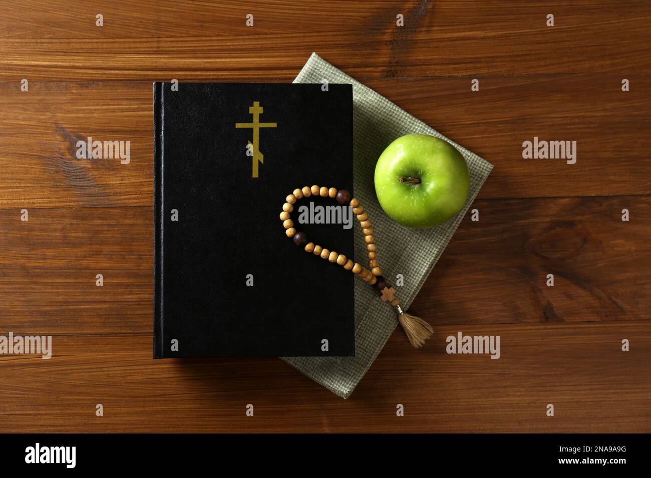 Bible, rosary beads and apple on wooden table, flat lay. Lent season ...