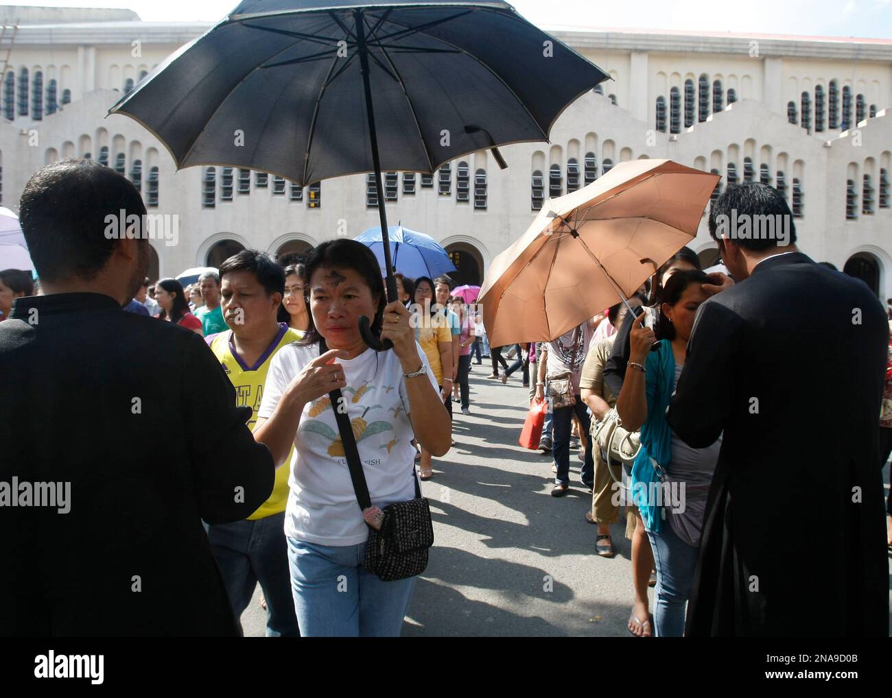 Priests mark the foreheads of devotees with black ashes in the sign of ...