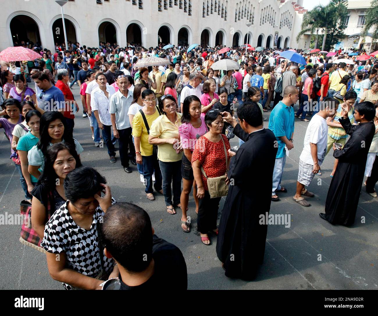 Priests mark the foreheads of devotees with black ashes in the sign of ...