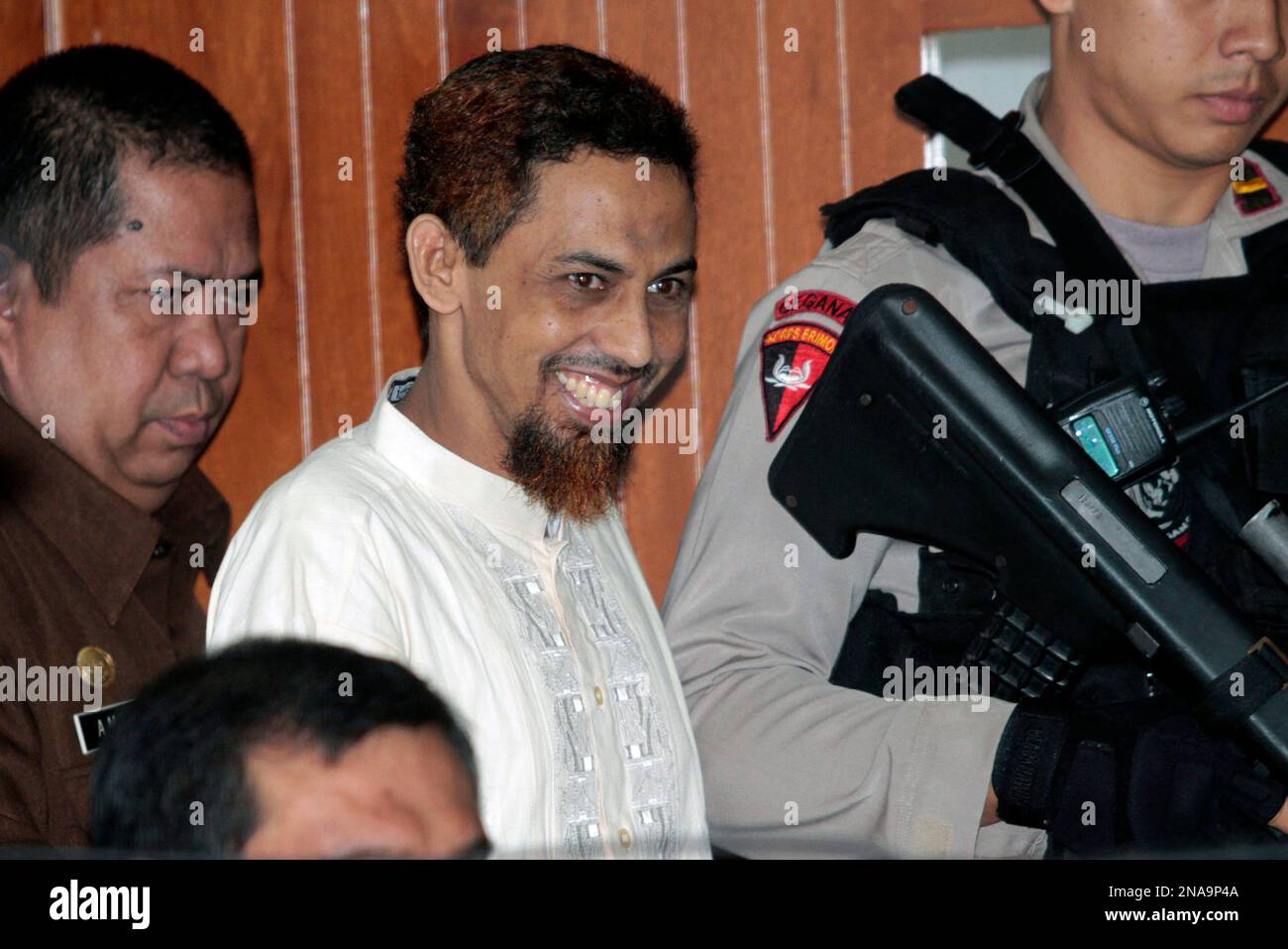 Indonesian militant Umar Patek, center, smiles as he enters the ...