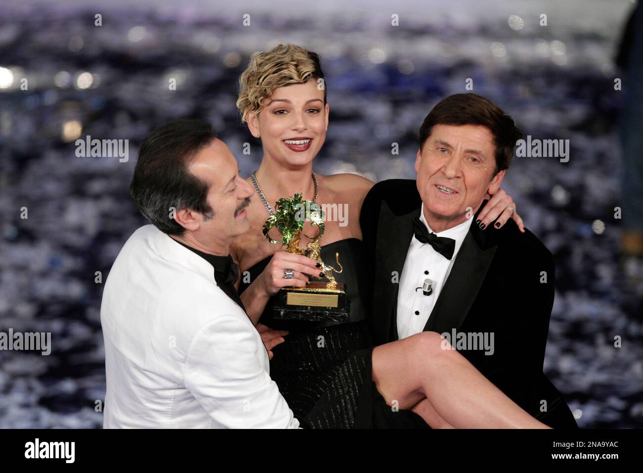 Italian singer Emma holds her trophy while she is carried by Italian show host Gianni Morandi ...