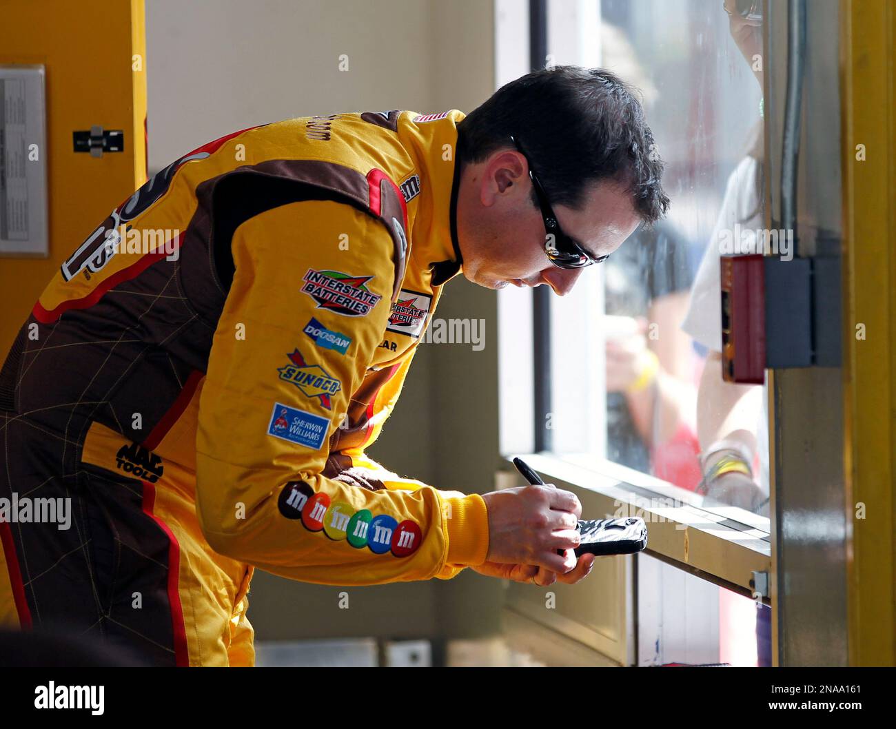 Kyle Busch signs autographs for fans through a window in his garage ...
