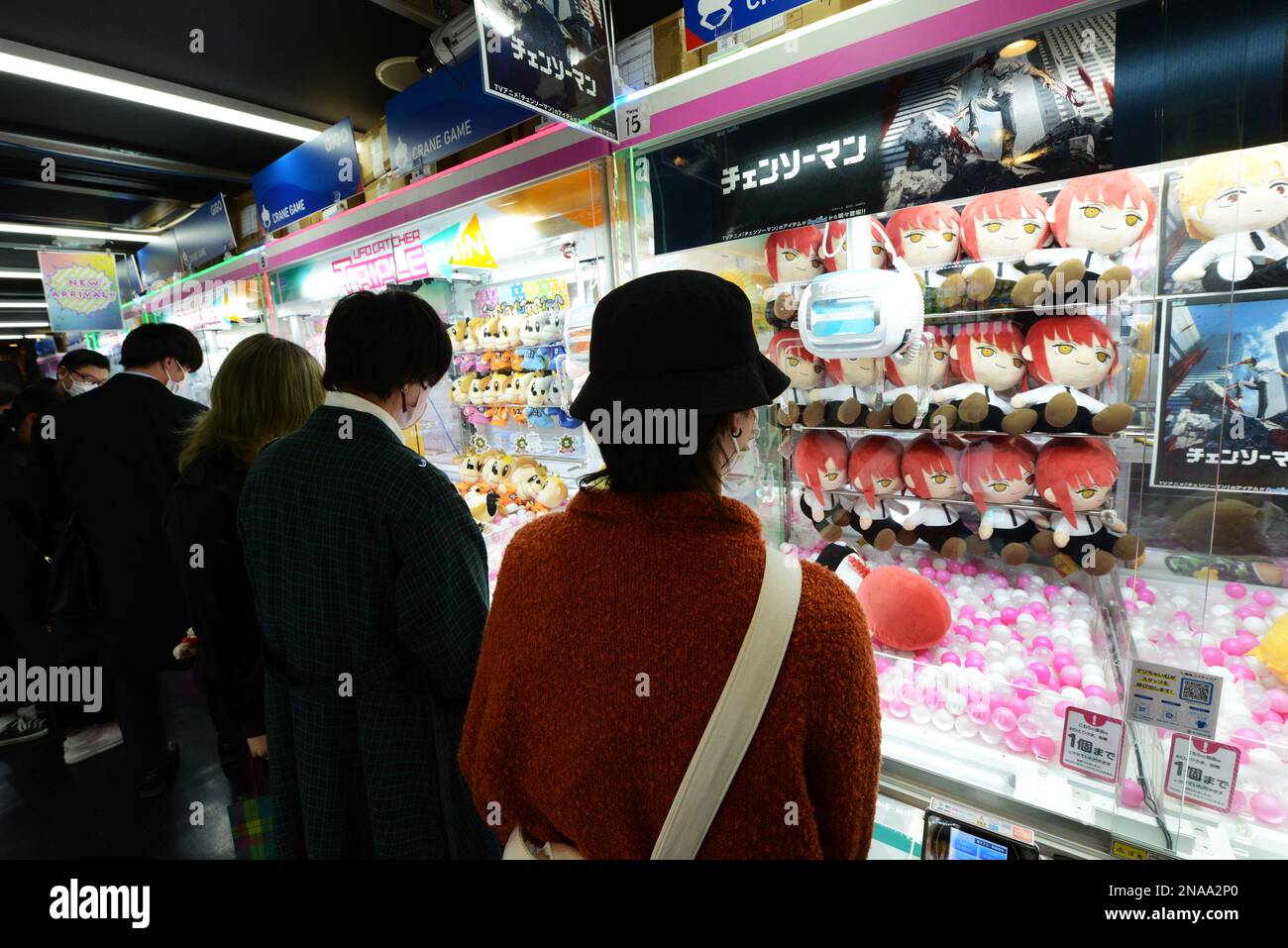 Japanese teenagers trying to pick toys in a toy crane claw machine ...