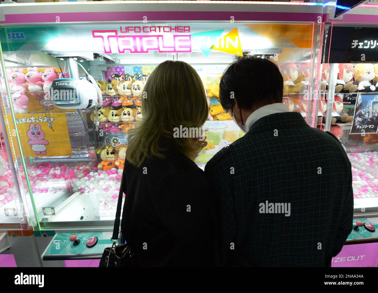 Japanese teenagers trying to pick toys in a toy crane claw machine in ...