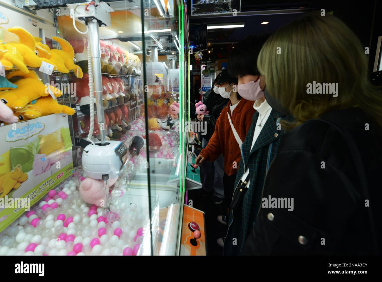 Japanese teenagers trying to pick toys in a toy crane claw machine in ... Japanese teenagers trying to pick toys in a toy crane claw machine in ...