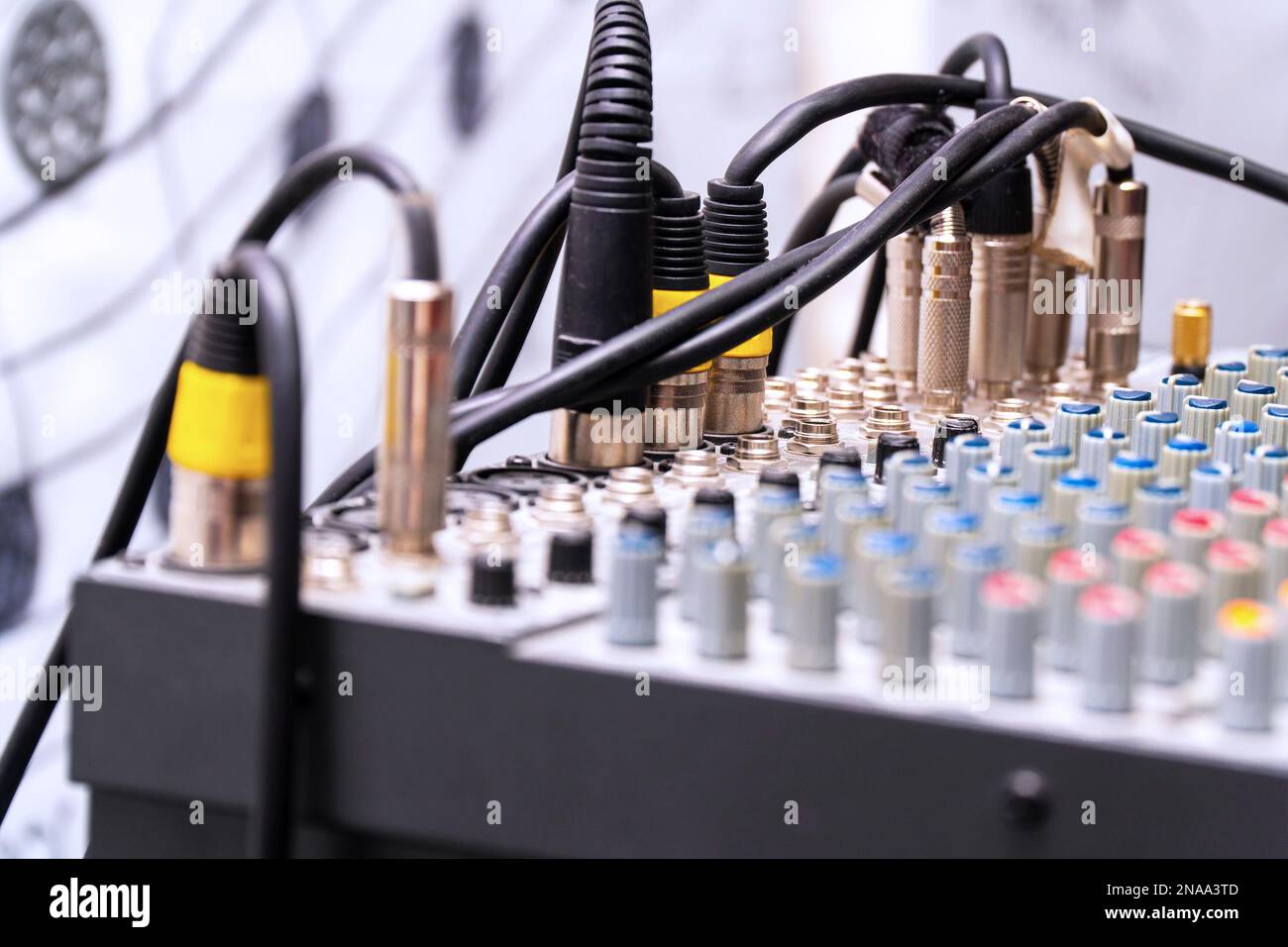 A small mixing console with cables with jacks inserted into console ...