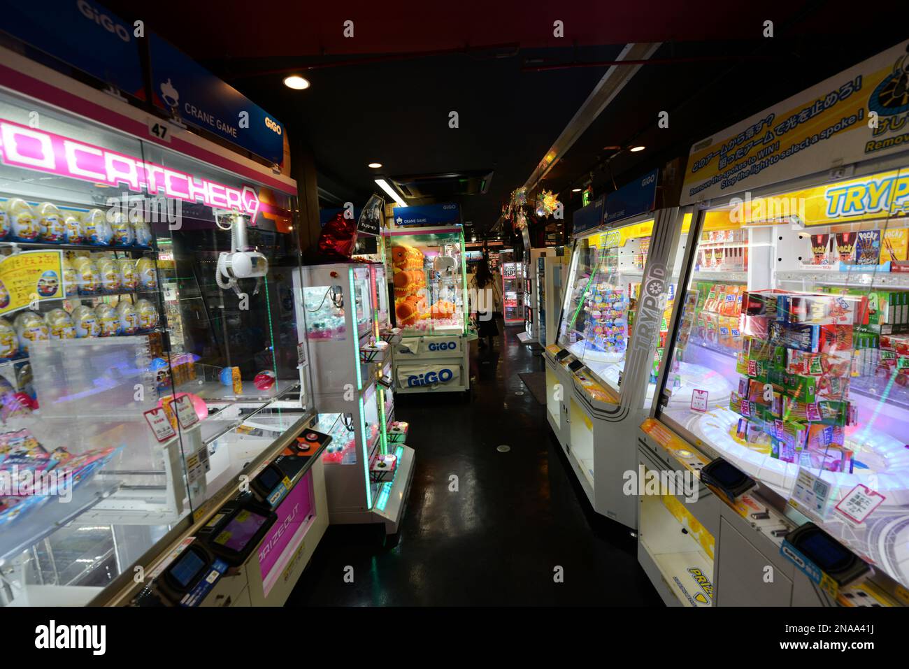 Japanese teenagers trying to pick toys in a toy crane claw machine in ...