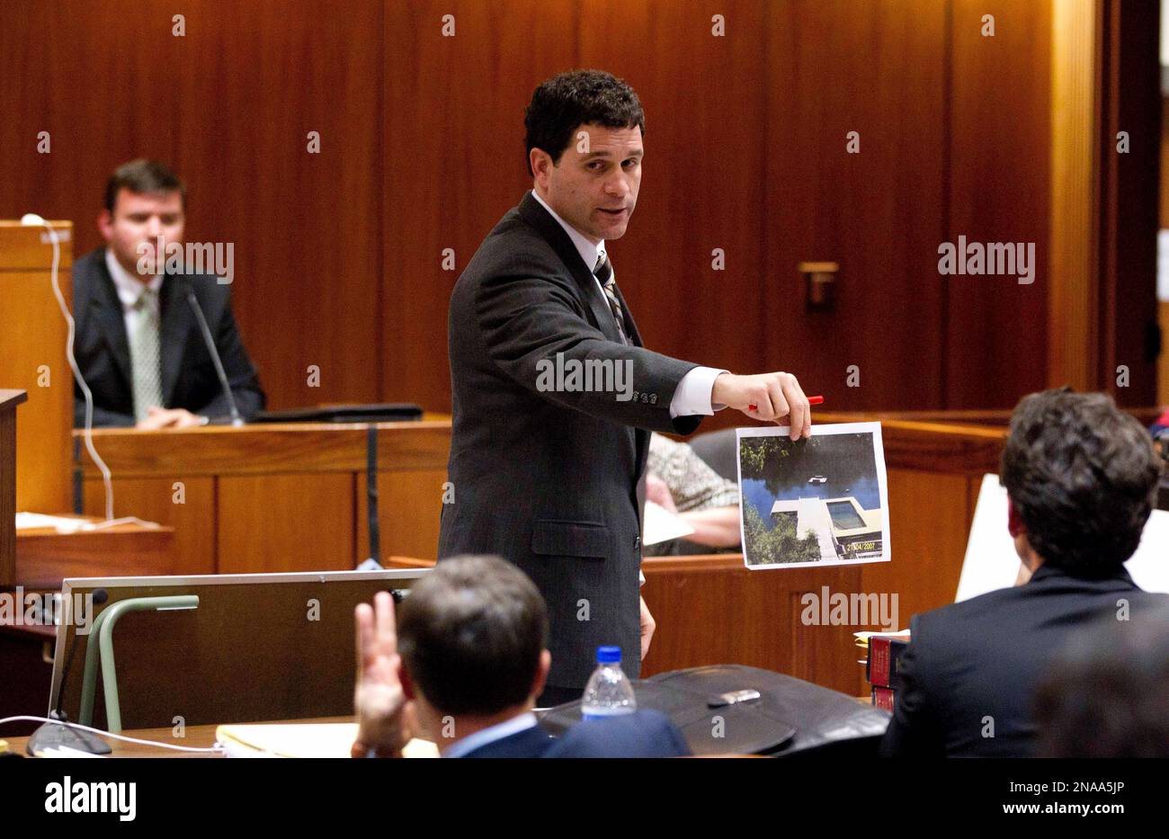 Defense attorney Brett Bloomston shows a photo to the prosecution table ...