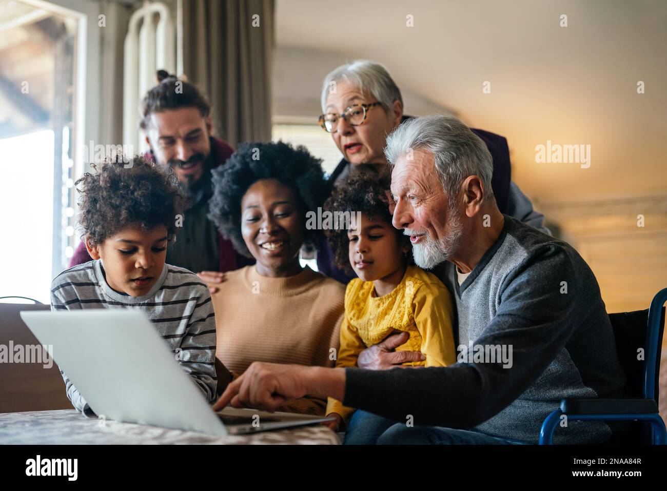 Happy multi-generation family gathering around notebbok and having fun ...