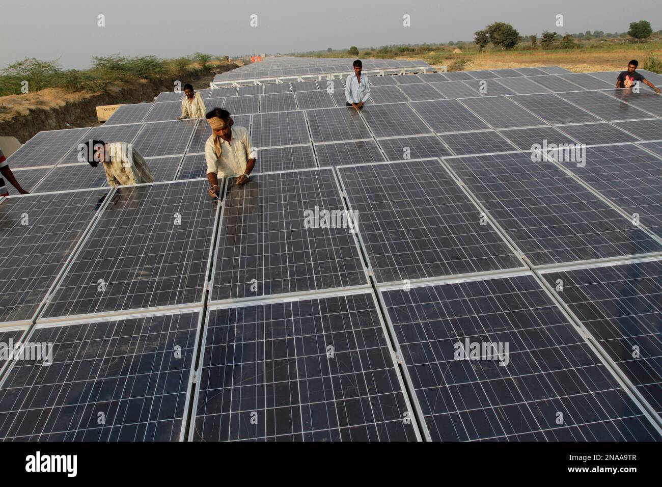 Indian laborers work amid installed solar panels atop the Narmada canal ...
