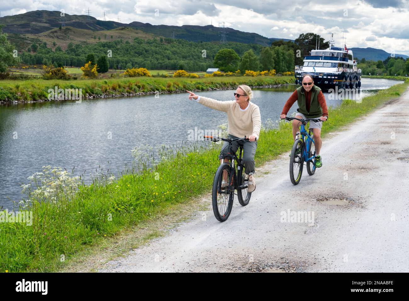 A man and woman ride bicycles along the Caledonian Canal tow path near ...