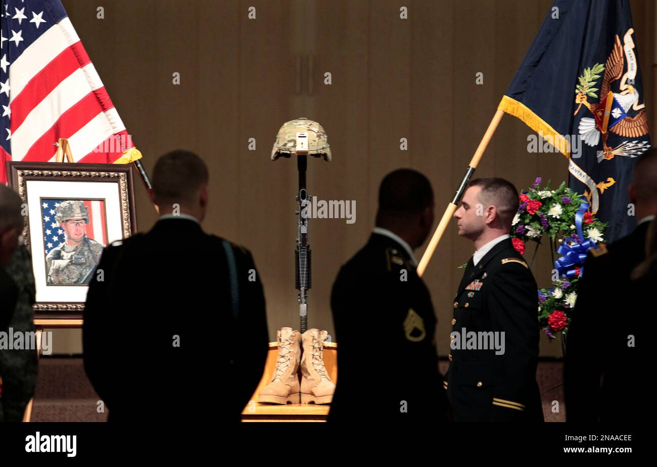 Soldiers file past a ceremonial fallen soldier battle cross of helmet ...
