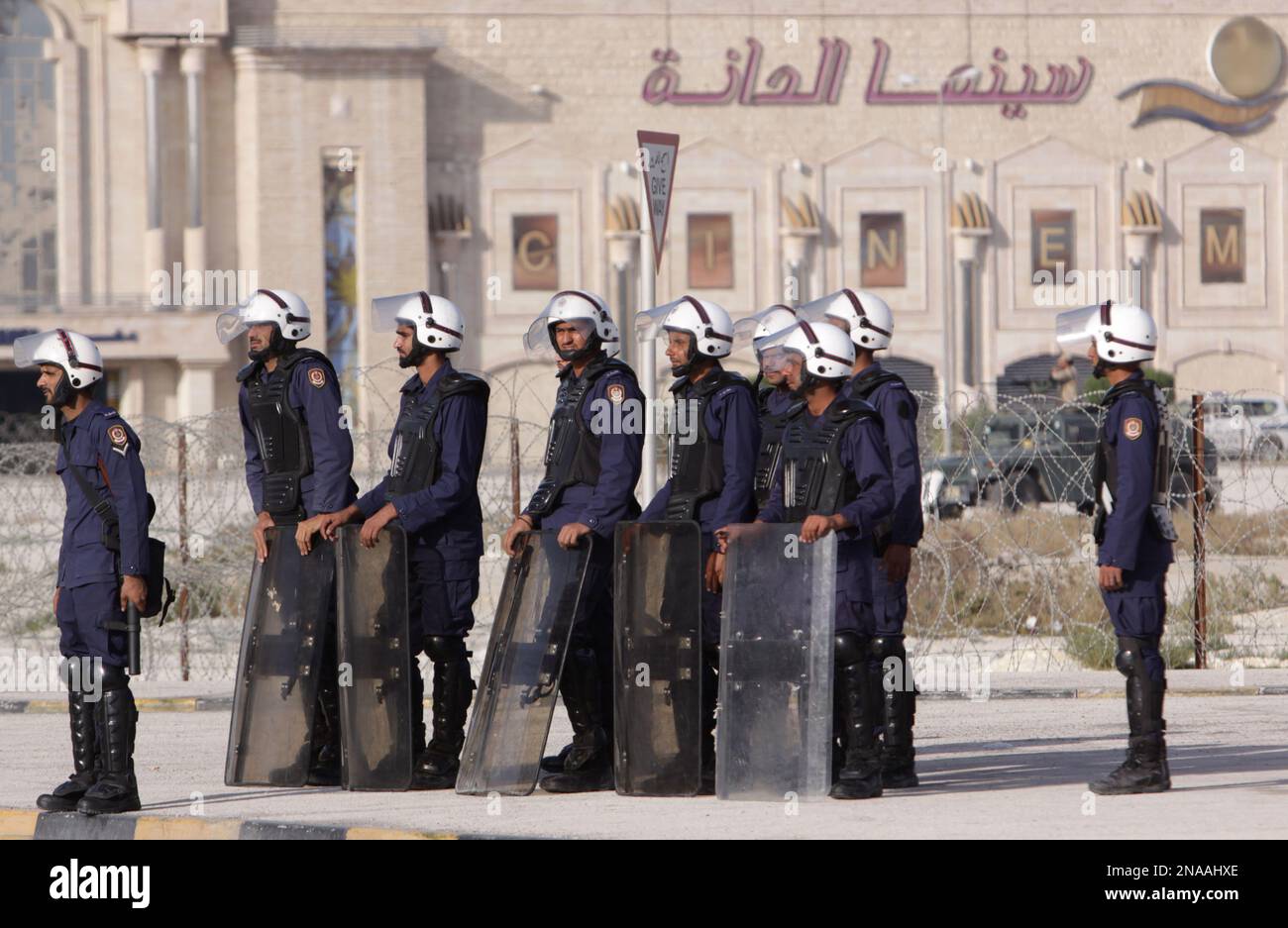 A line of riot police stand in front of razor wire near a shopping mall ...