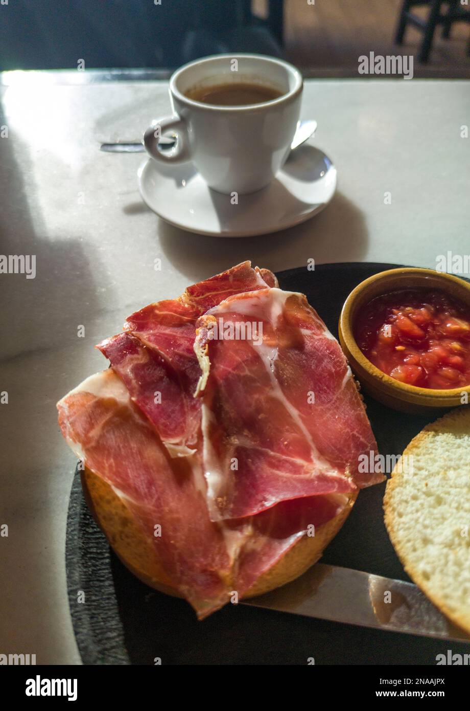 Cured ham toast with grinded tomato for breakfast. Coffee cup at bottom ...