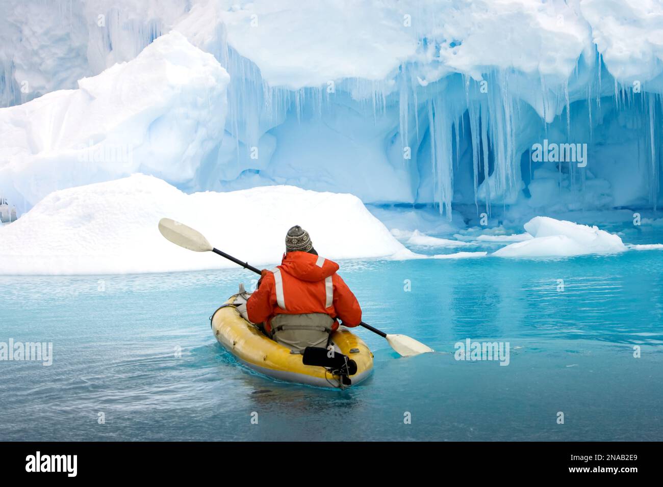 A man in a kayak explores an iceberg near Peterman Island Stock Photo ...