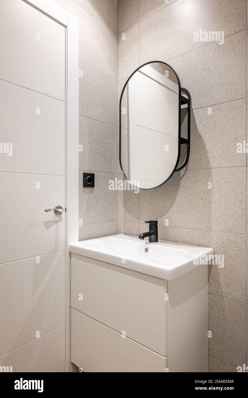 Corner of a bathroom with a white sink on a vanity with two large ...