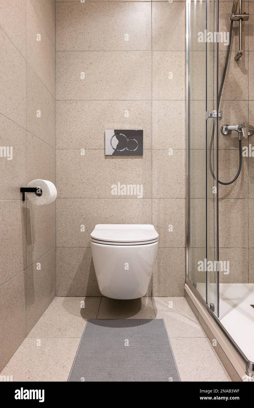 Toilet with walls and floor in soft beige square tiles. The white ...
