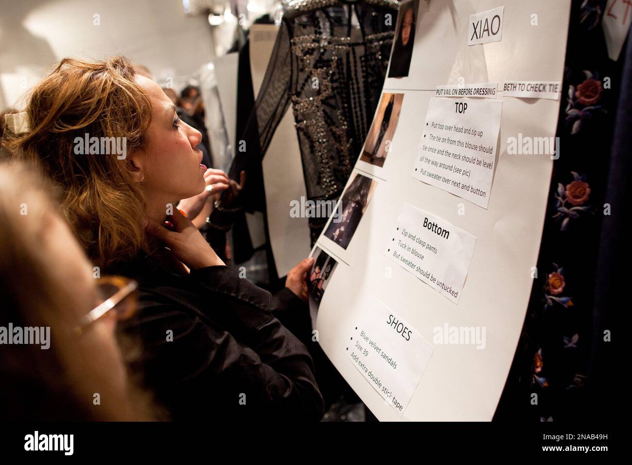 Staff members study posters with dressing instructions backstage before ...
