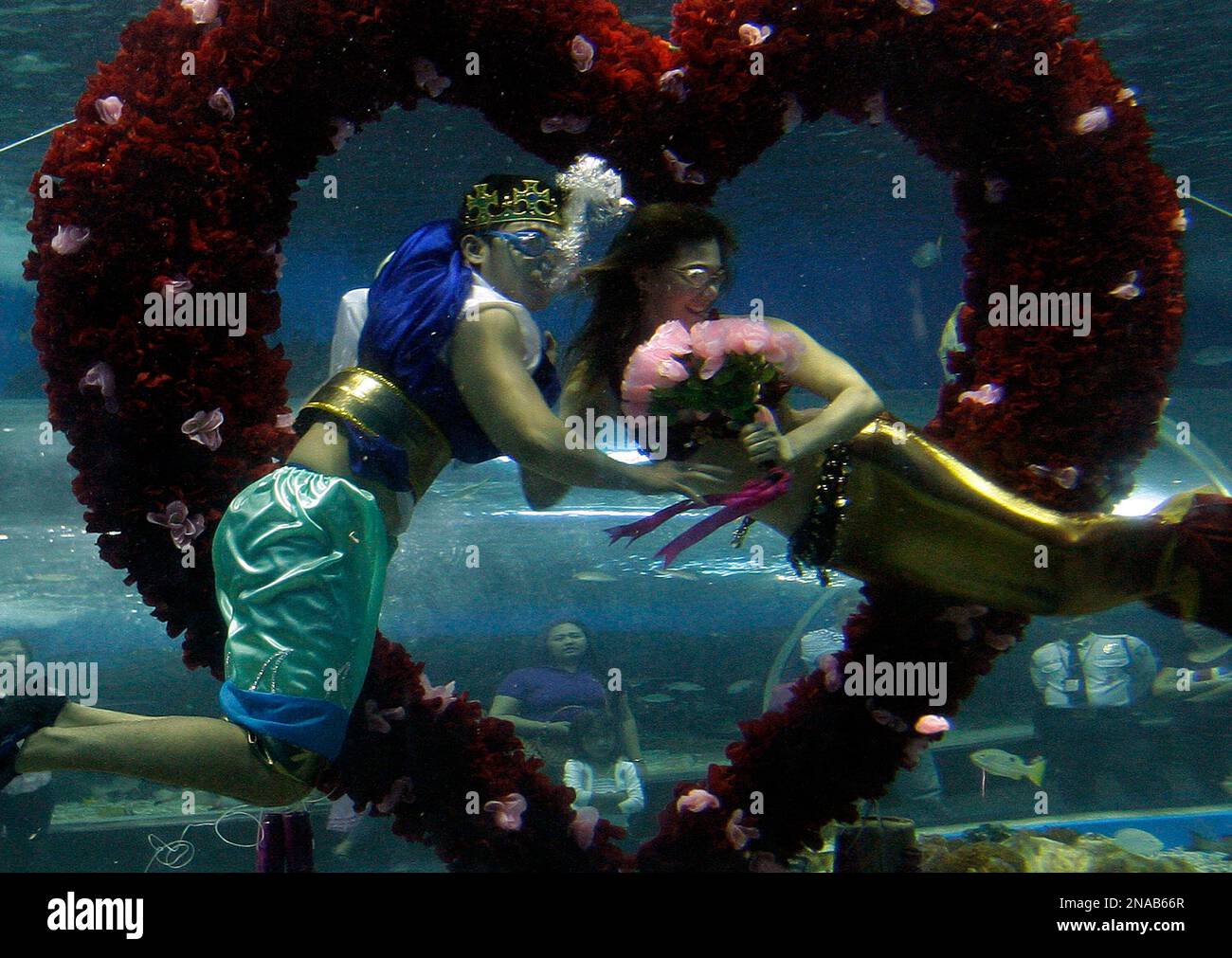 Divers portraying Poseidon and mermaid perform beside a bunch of ...