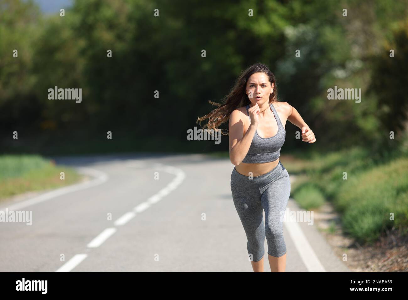 Front view portrait of a woman running fast on a road Stock Photo - Alamy