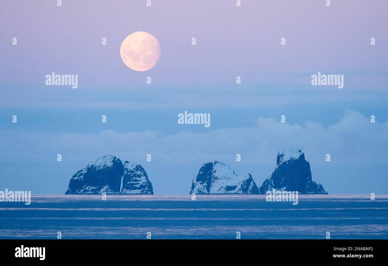 Full moon sets over two mountainous islands in the Gerlache Strait off ...
