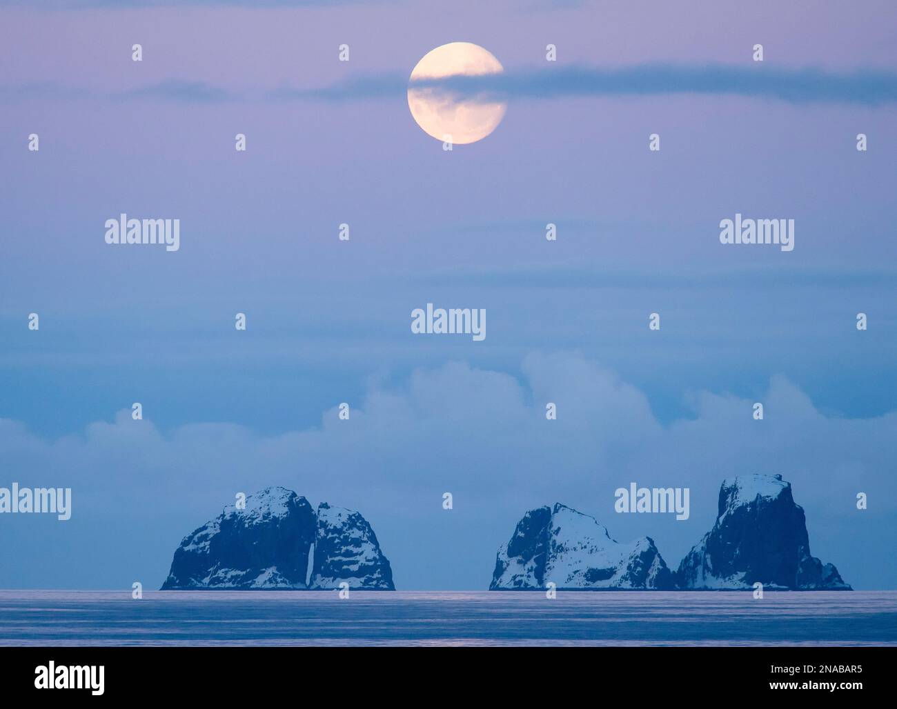 Full moon sets over two mountainous islands in the Gerlache Strait off ...