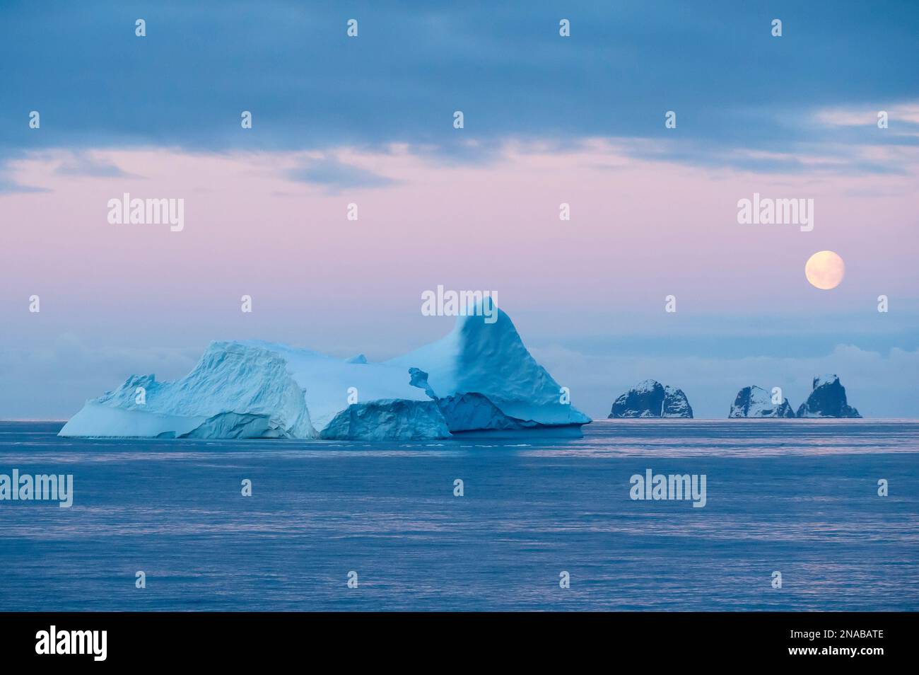 Full moon sets over icebergs and mountainous islands in the Gerlache ...