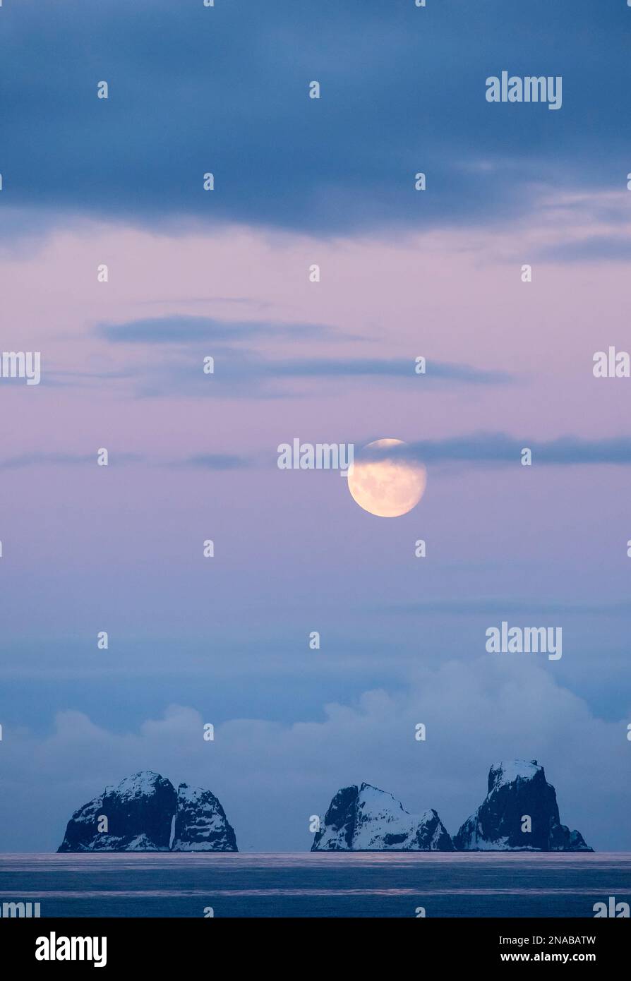 Full moon sets over two mountainous islands in the Gerlache Strait off ...