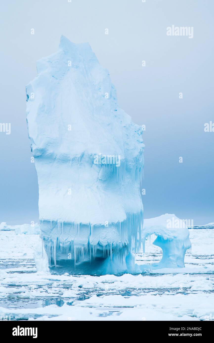 An unusually shaped iceberg floats amidst pack ice in the Southern ...