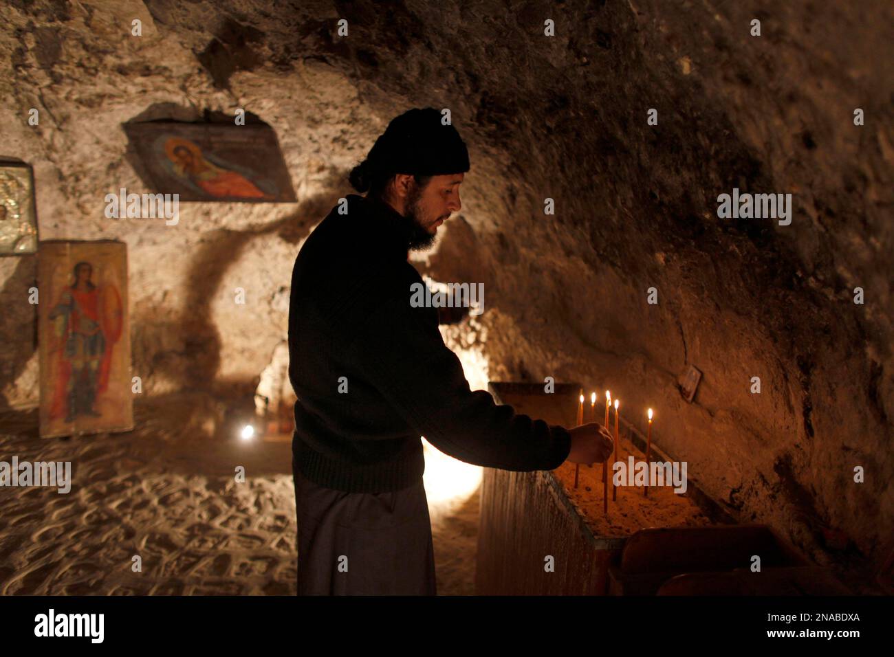 File - In this Jan. 16, 2012 file photo a Greek Orthodox monk lights a ...