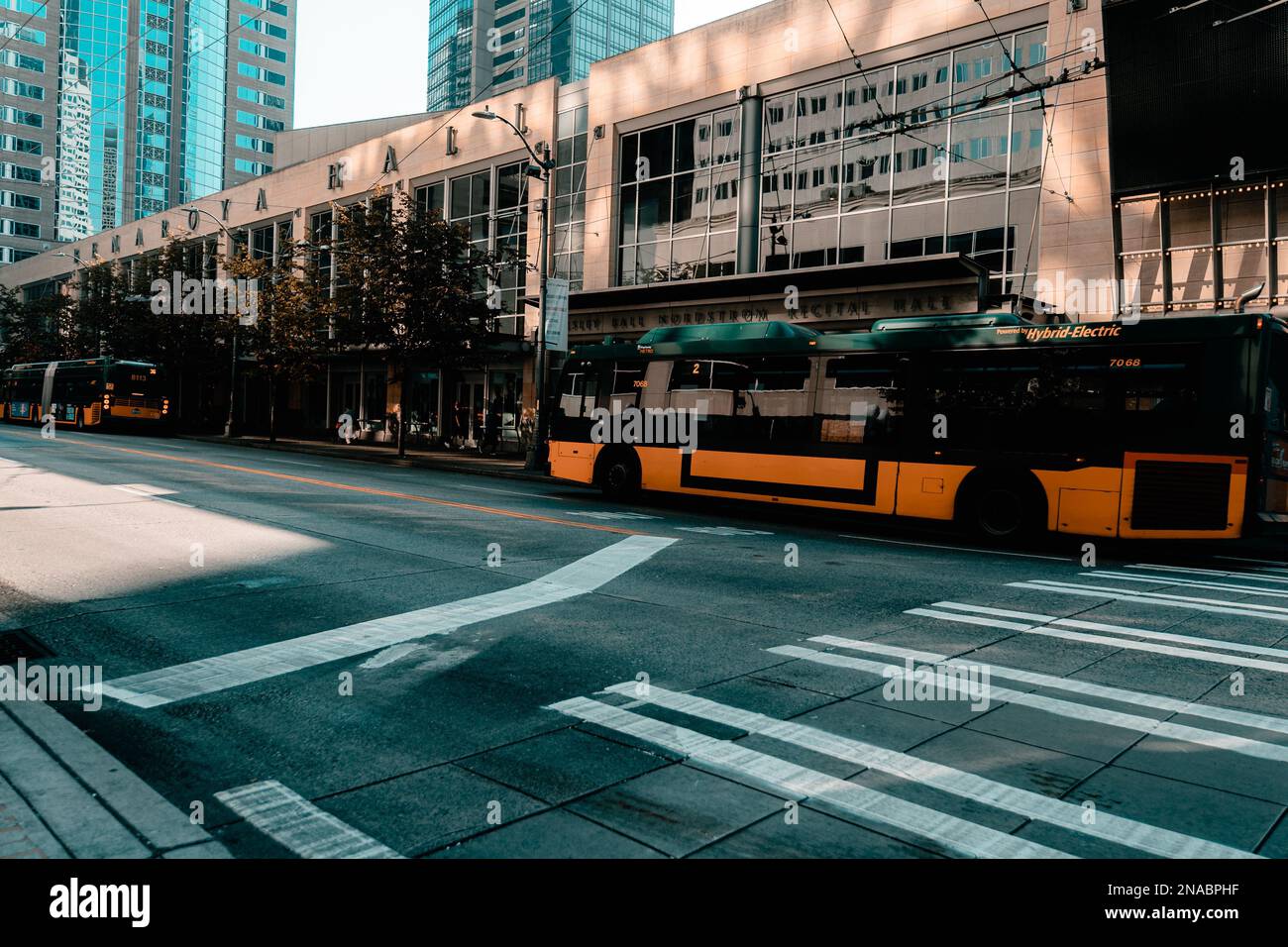 An urban street and two public transportation buses parked on a street ...