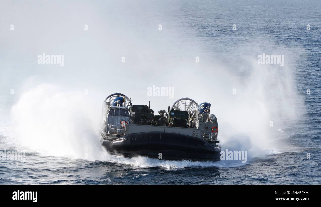 A LCAC loaded with artillery and trucks approaches the well deck during ...