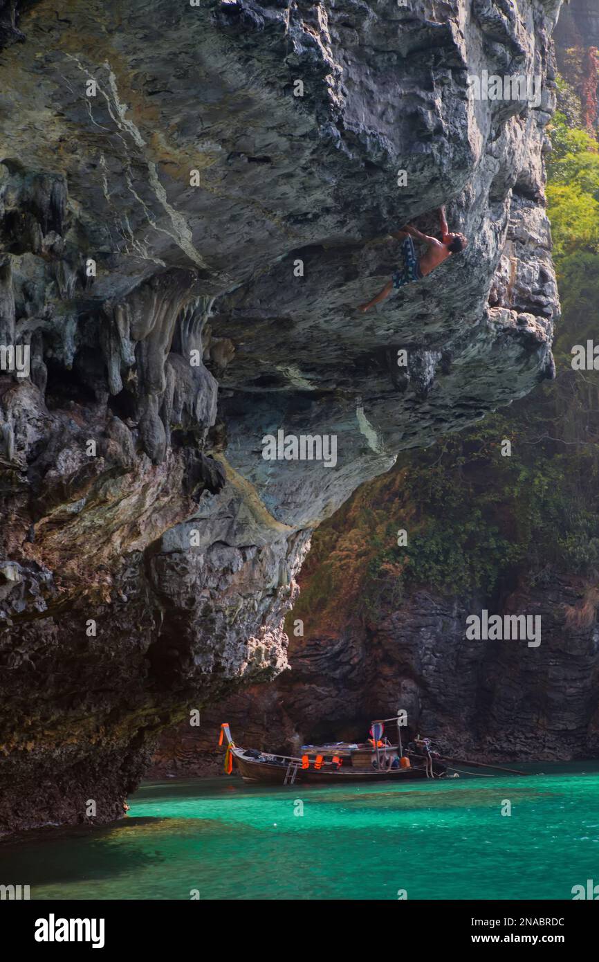 A climber deep water soloing on the limestone cliffs of a karst Stock ...