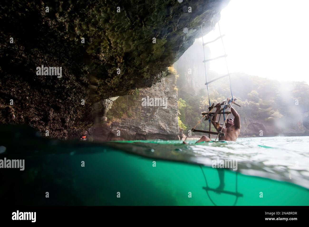 A climber climbs a ladder to reach a deep water soloing route Stock ...