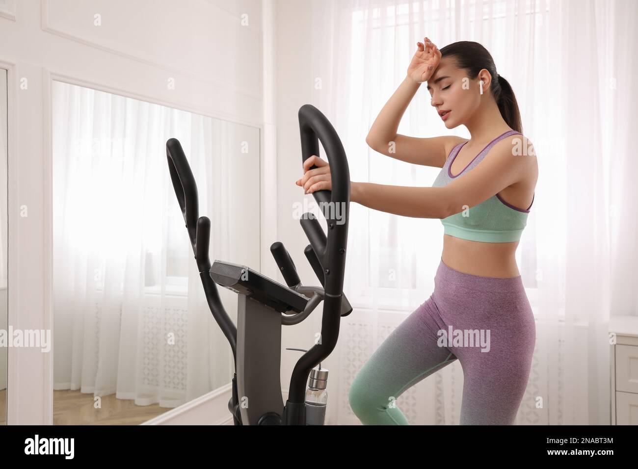 Tired woman after training on modern elliptical machine at home Stock ...