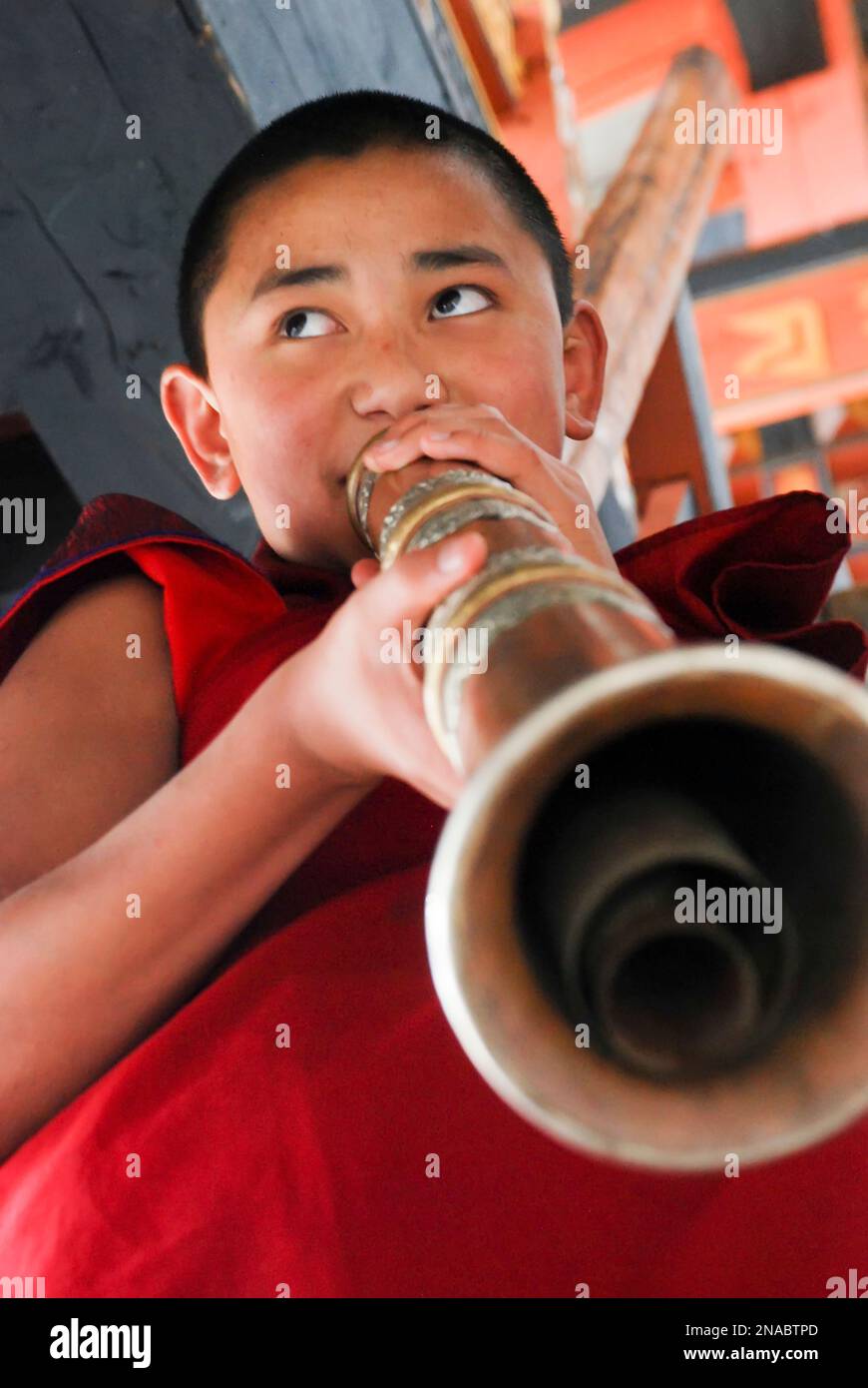 In the Punakha Dzong of Punakha, Bhutan, a young monk plays a lingm, a ...