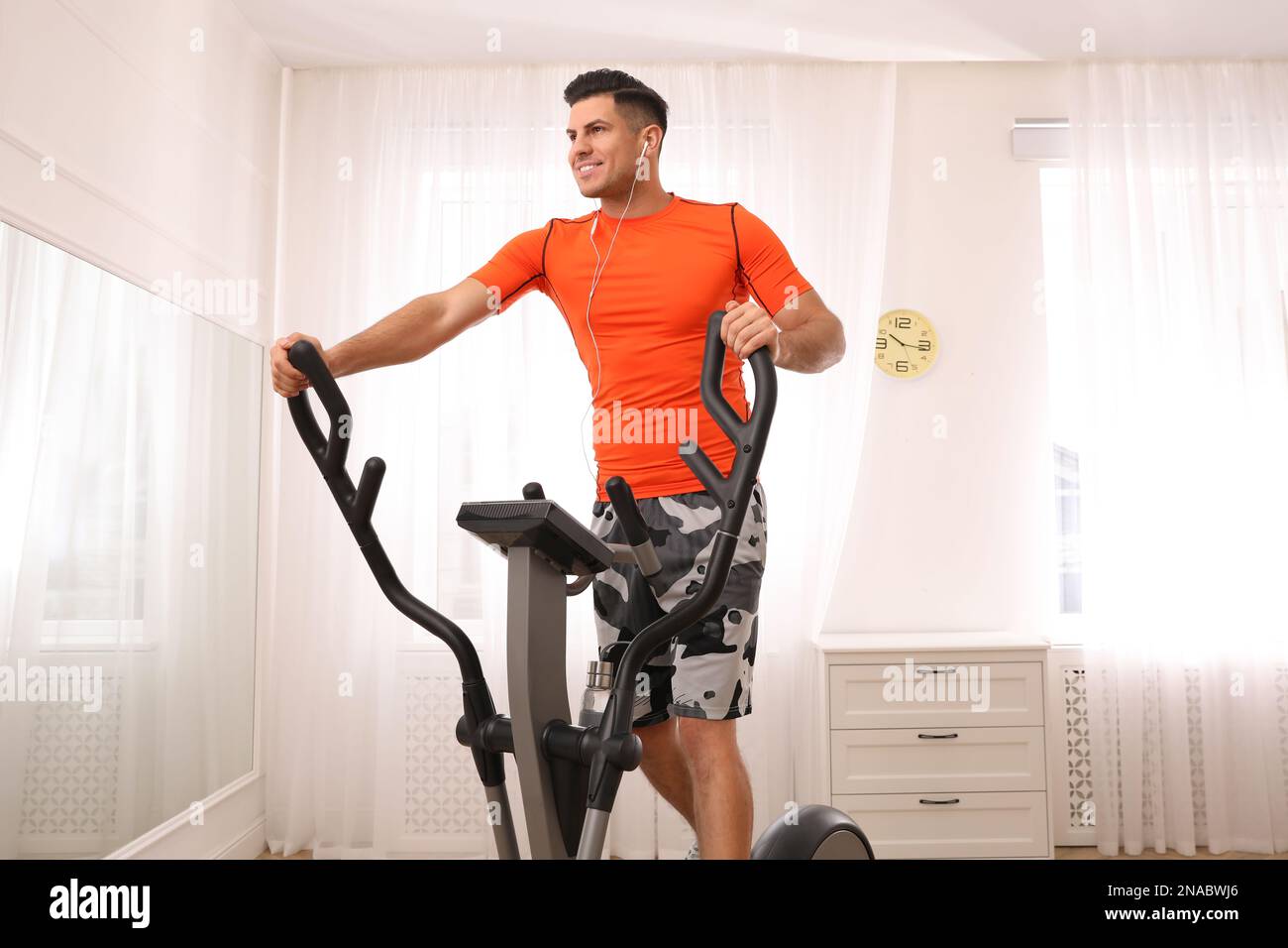 Man using modern elliptical machine at home Stock Photo - Alamy