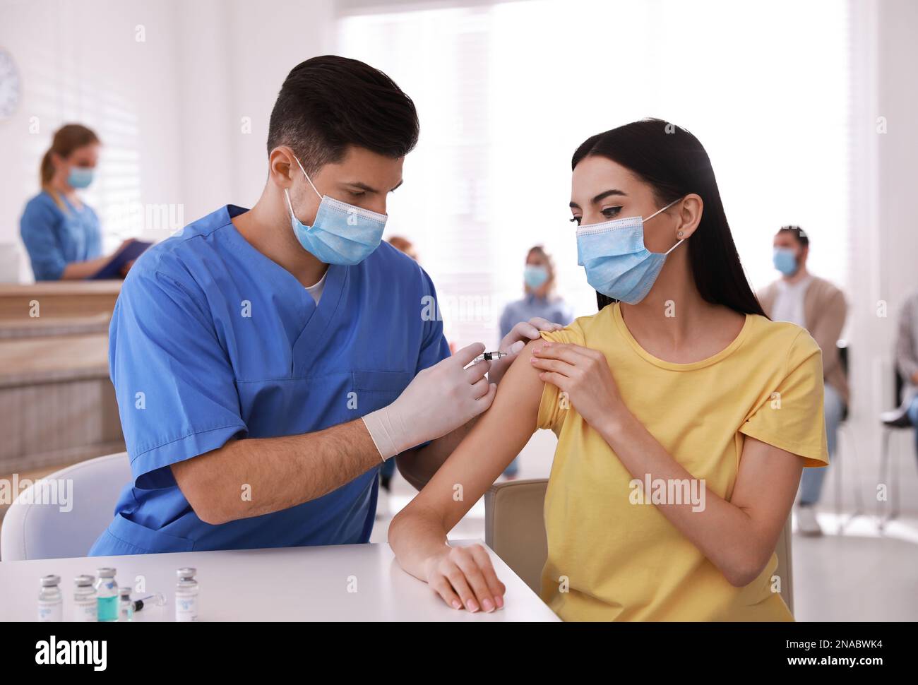 Doctor giving injection to patient while other waiting in line at ...