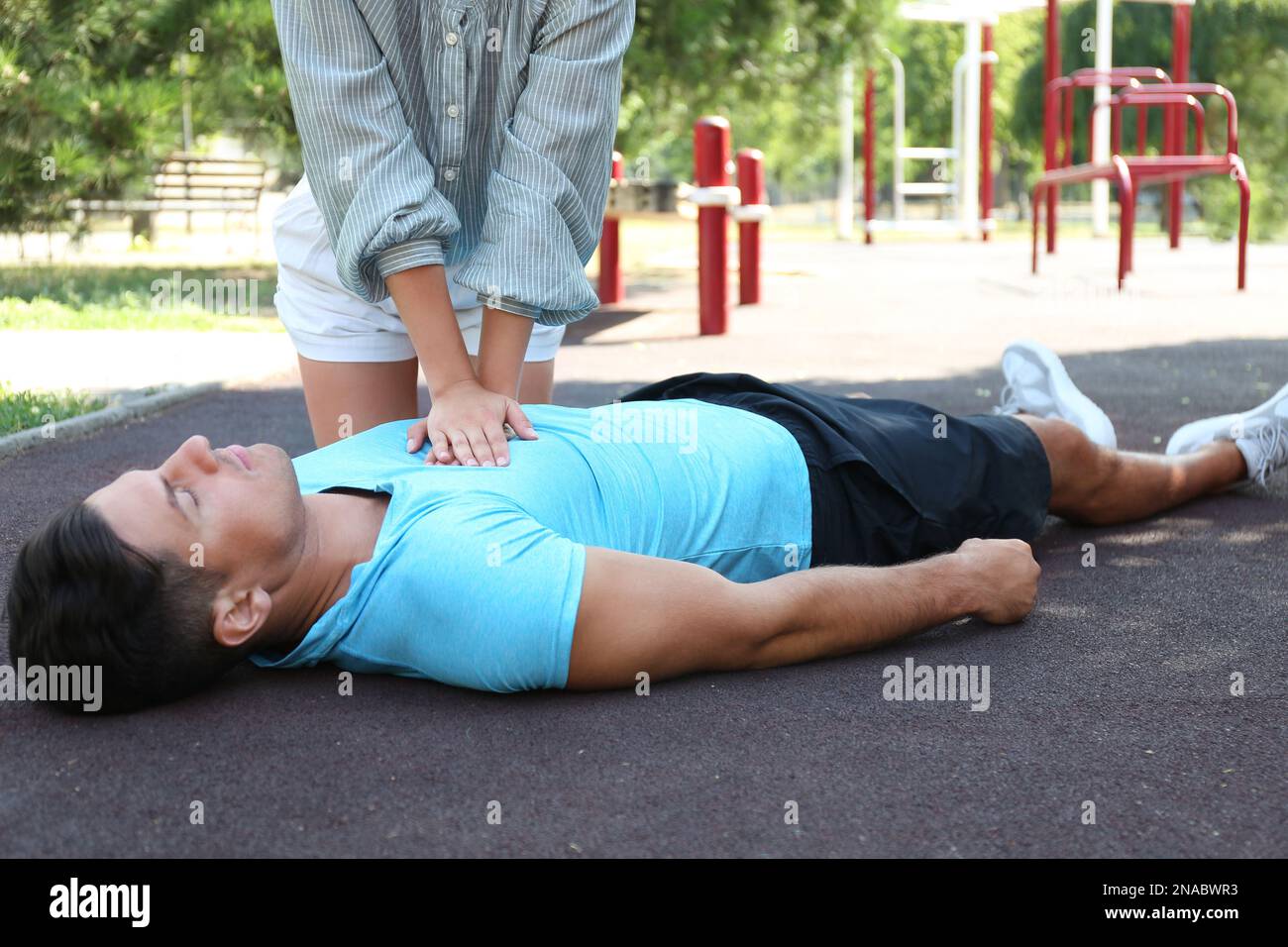 Young woman performing CPR on unconscious man outdoors. First aid Stock ...