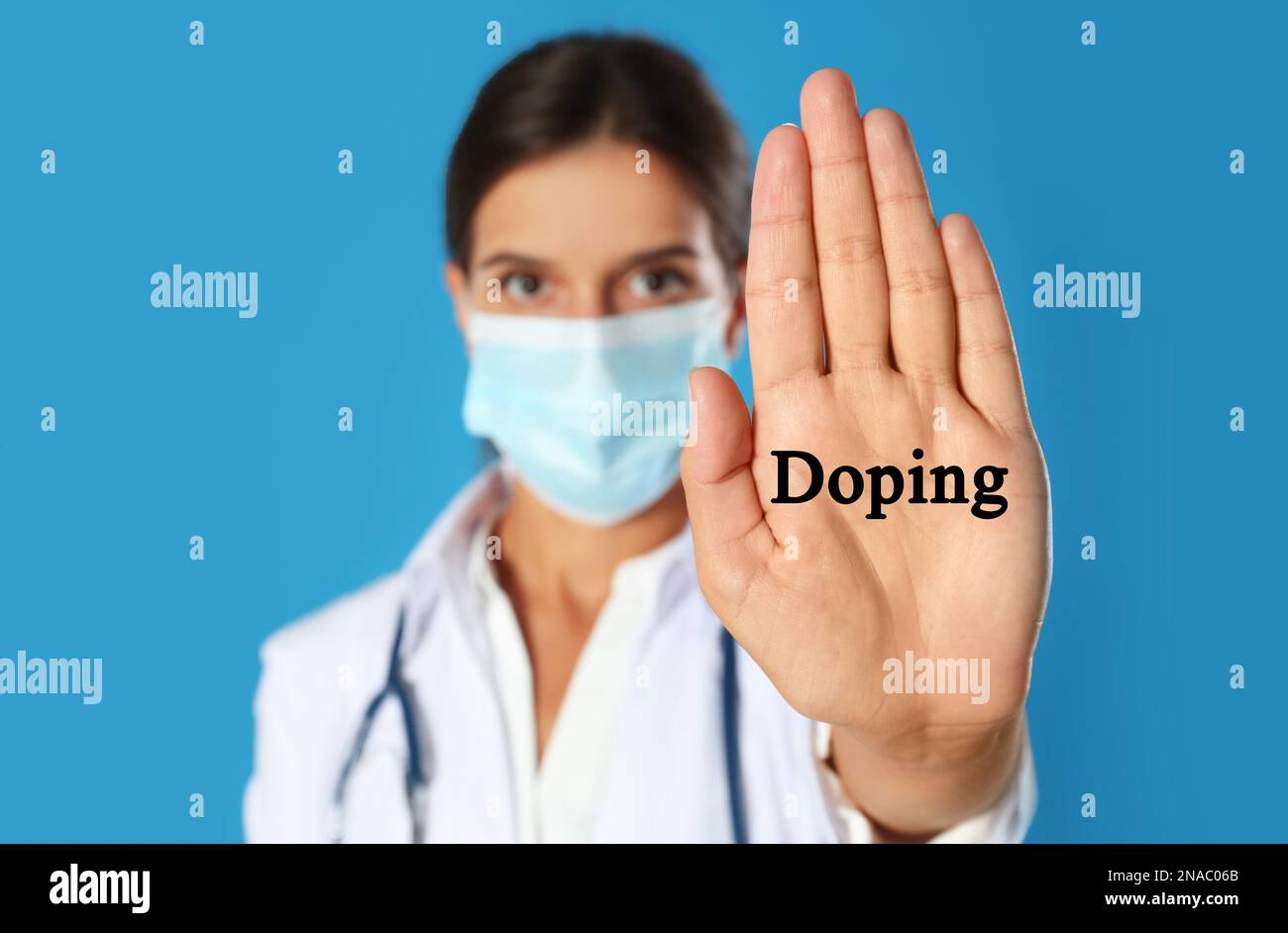 Doctor in protective mask showing stop gesture against blue background ...