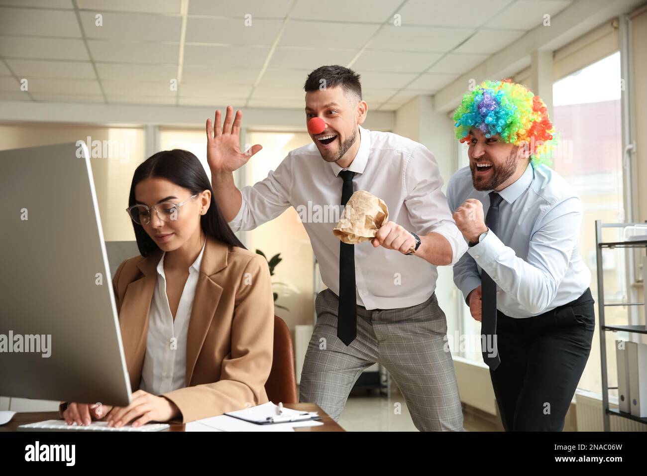 Men popping paper bag behind their colleague in office. Funny joke ...