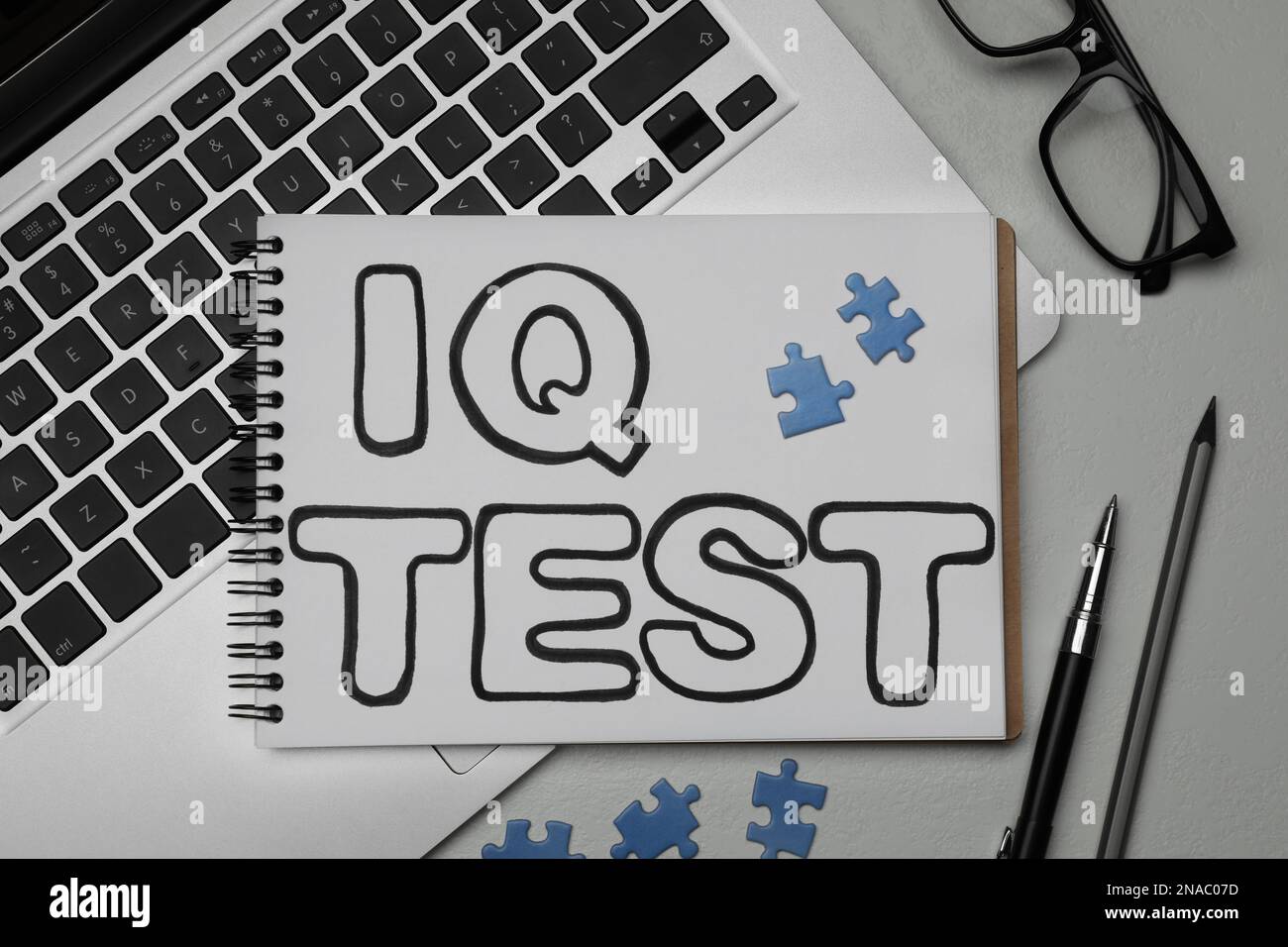 Notebook with words IQ Test, puzzles and laptop on white table, flat ...