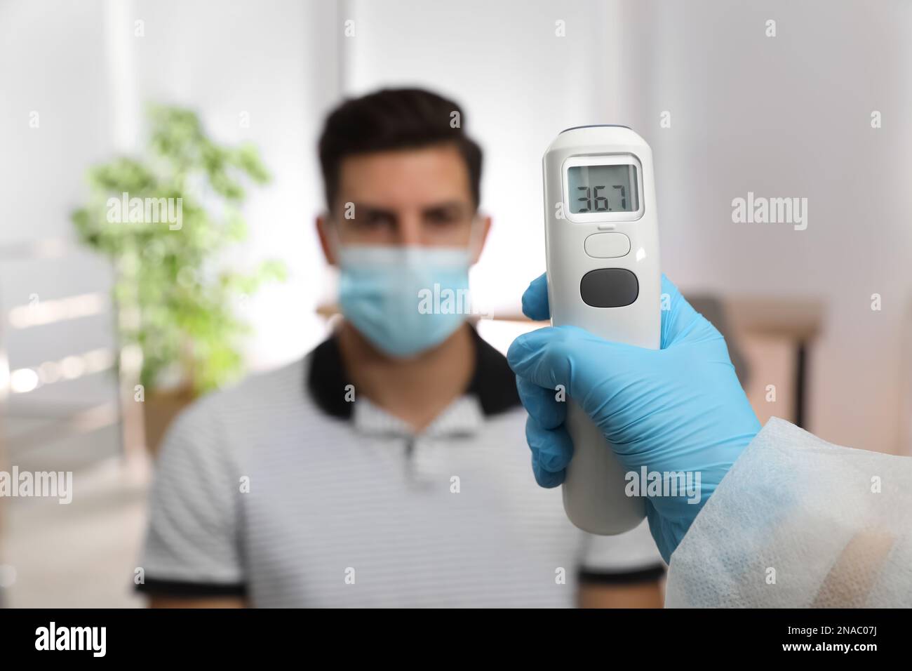 Doctor measuring man's temperature in office, closeup. Prevent ...