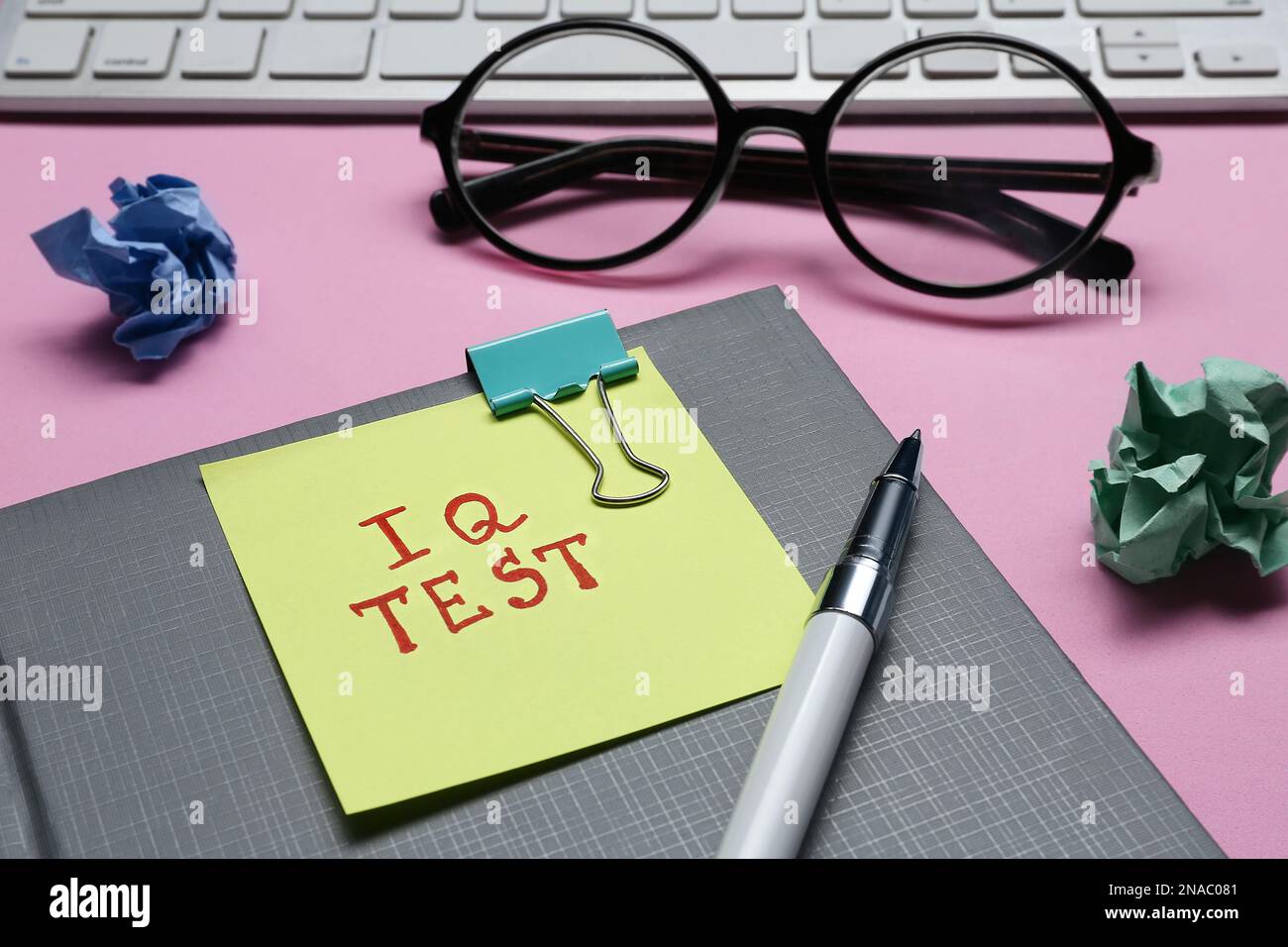 Sticker note with text IQ Test, notebook, pen, crumpled paper balls ...