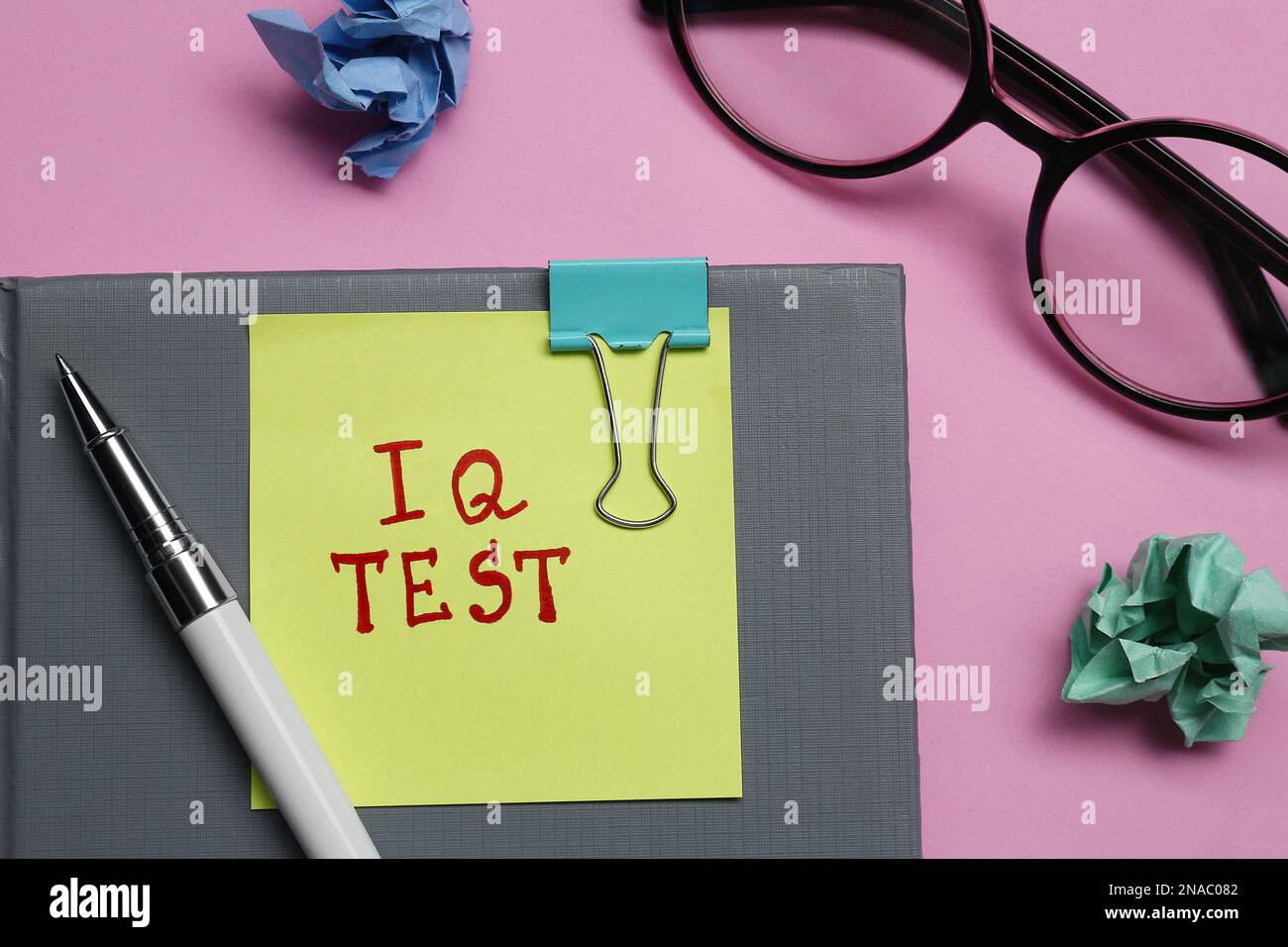 Sticker note with text IQ Test, notebook, pen, crumpled paper balls and ...