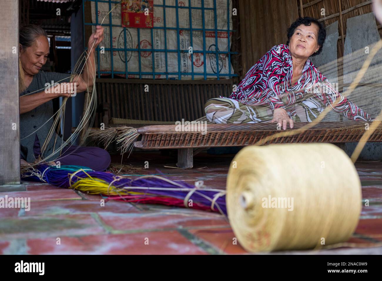 Two women work together to weave a rattan mat in Vietnam; Binh Thanh Island, Vietnam Stock Photo ...