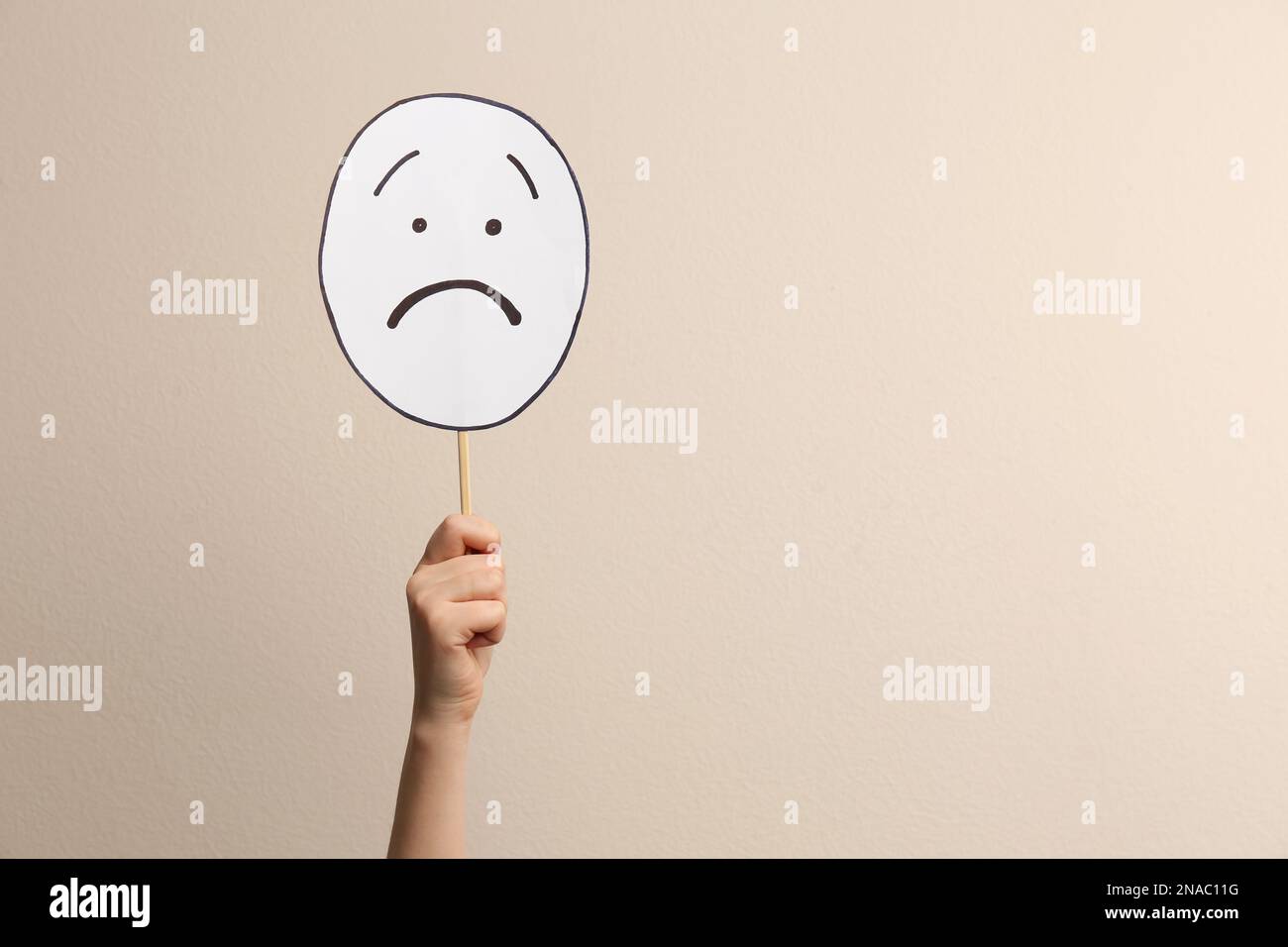 Woman with sad paper face on beige background, closeup. Space for text ...